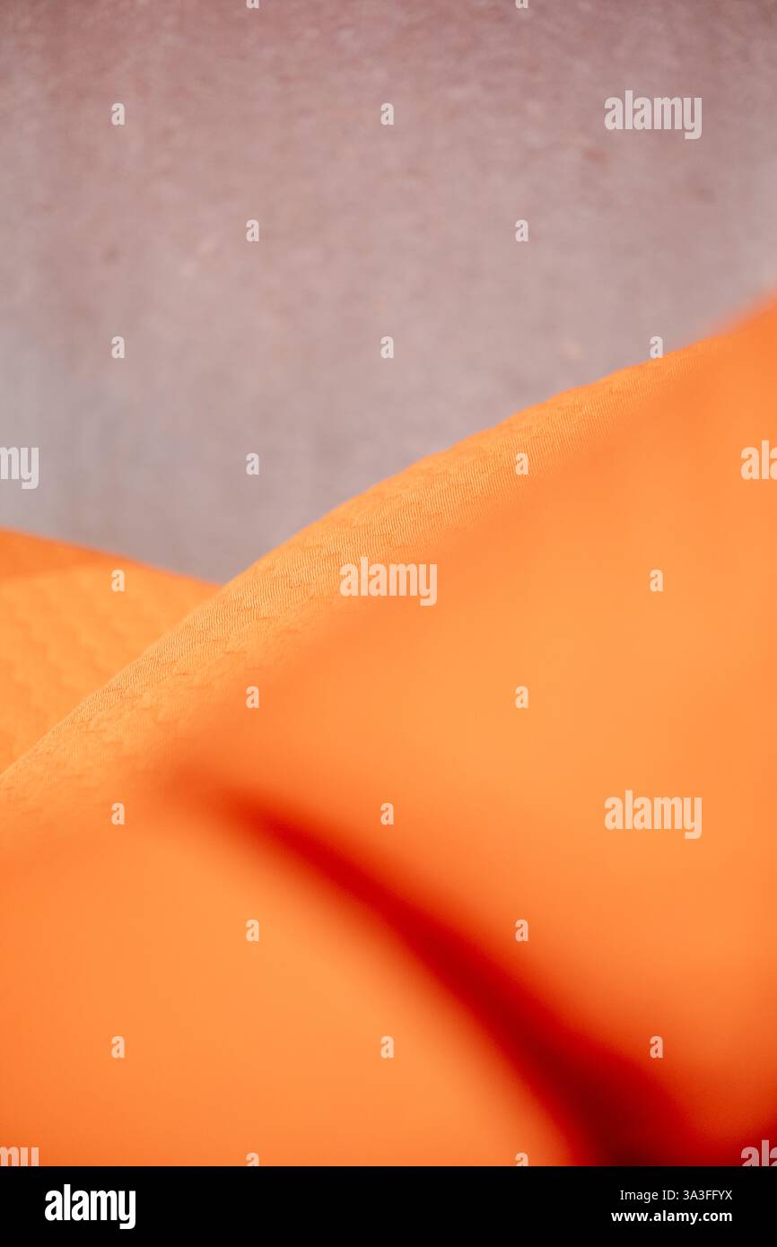 Orange fabric with soft shadows and a neutral background creates a ...