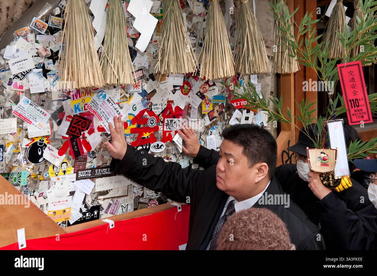 Worshipers touch wooden prayer panel covered with business cards ...