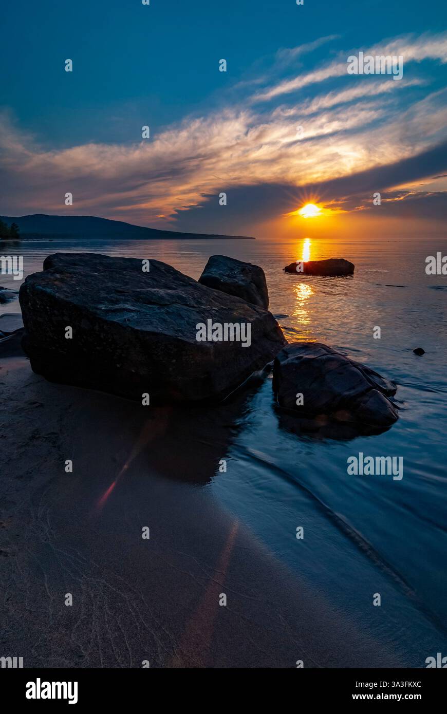 Large rocks on the Lake Superior Shore receive the last light of sunset ...