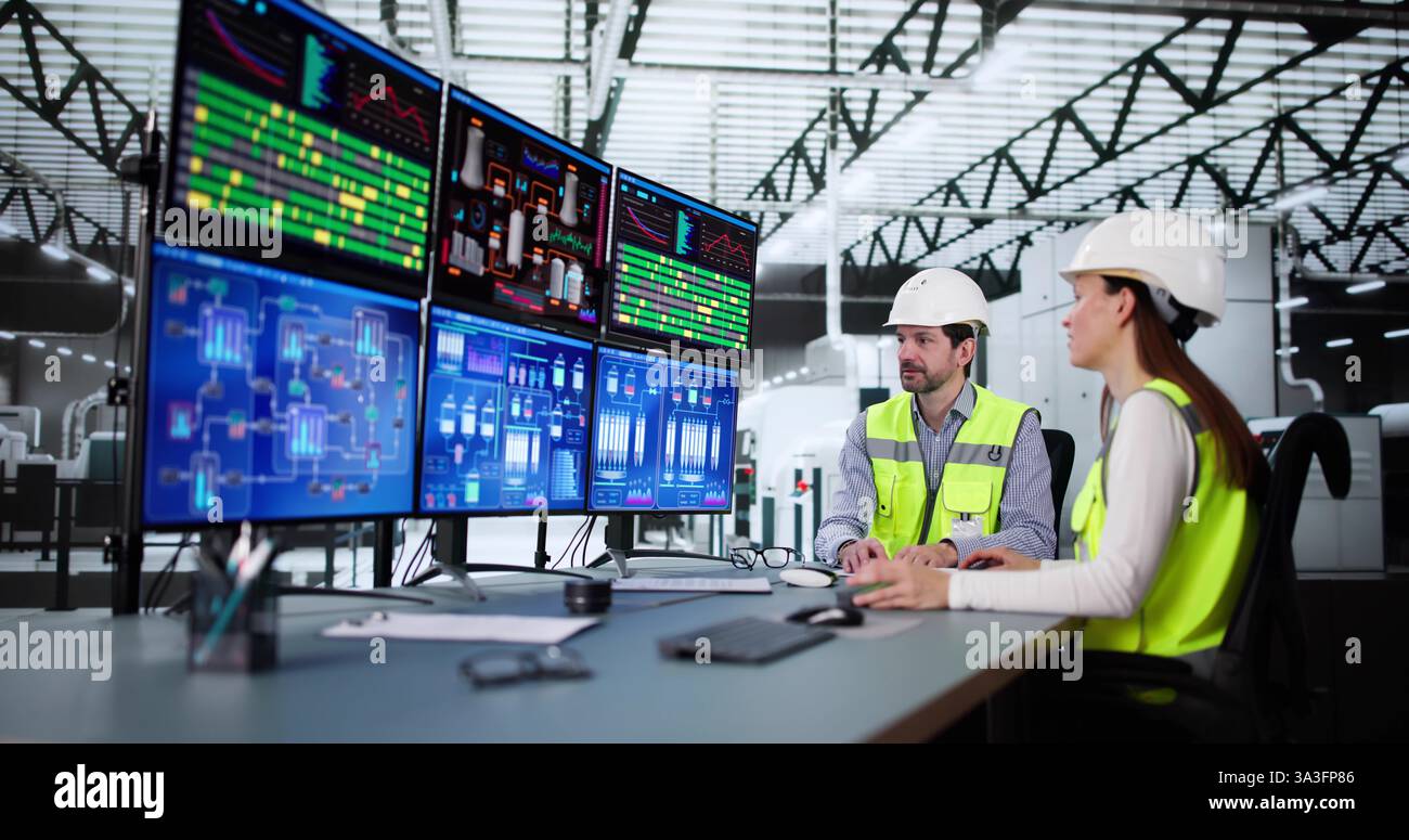 Operators and engineers monitor SCADA system using control in factory. Woman and man monitor ...