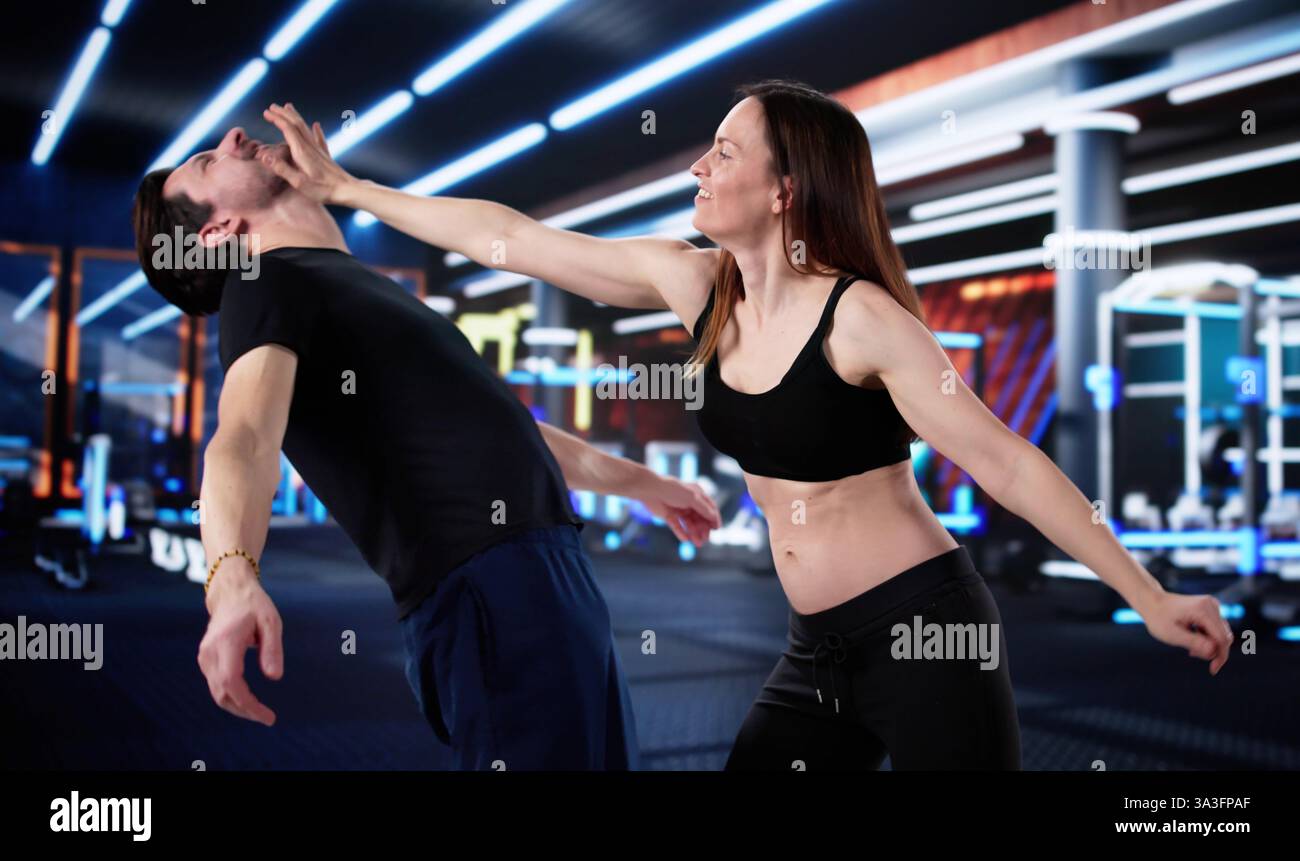Young woman learning self defense techniques with personal trainer at gym. Experienced couple ...