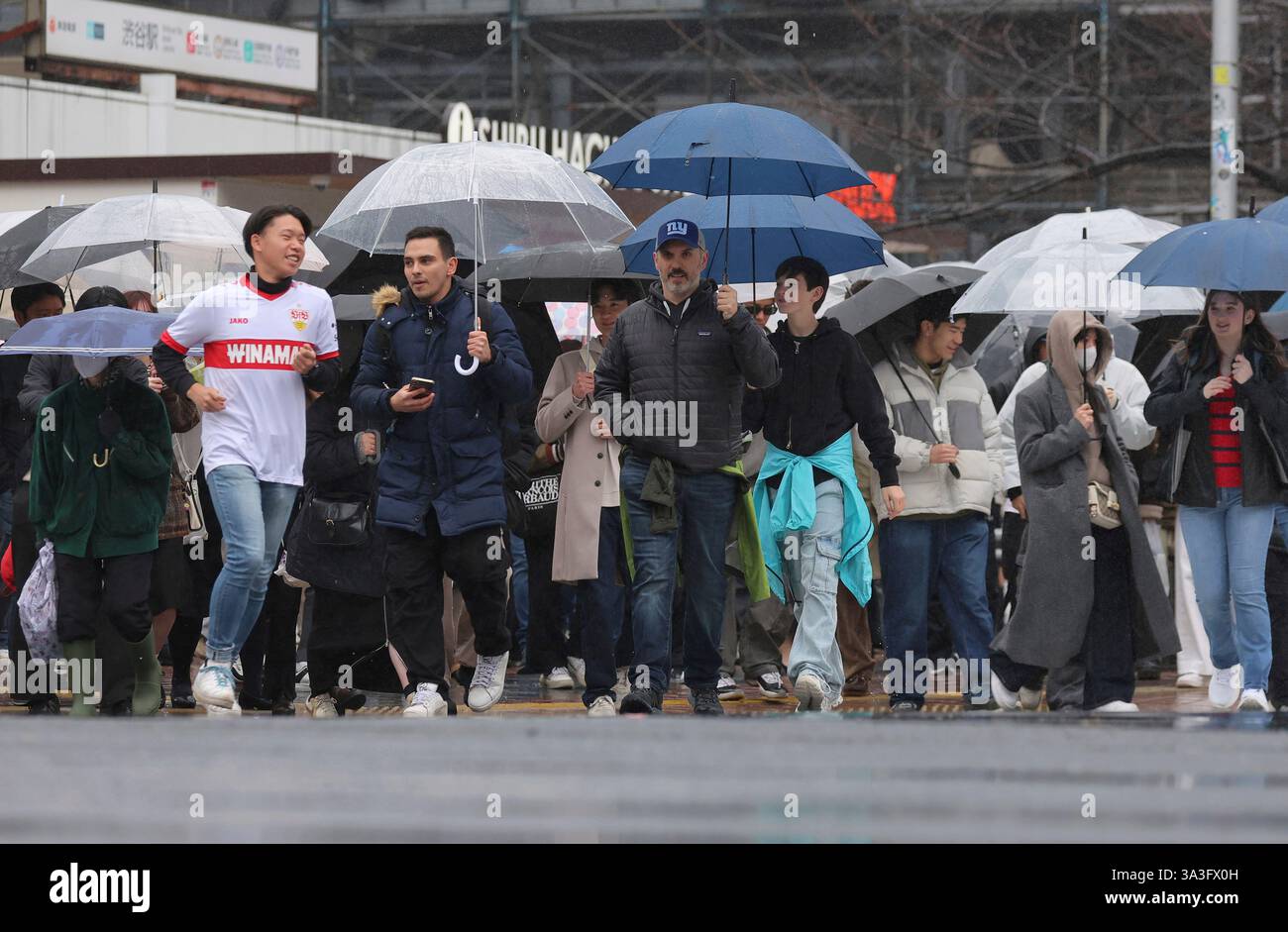 People walk with umbrella in cold rain near JR Shibuya station in ...