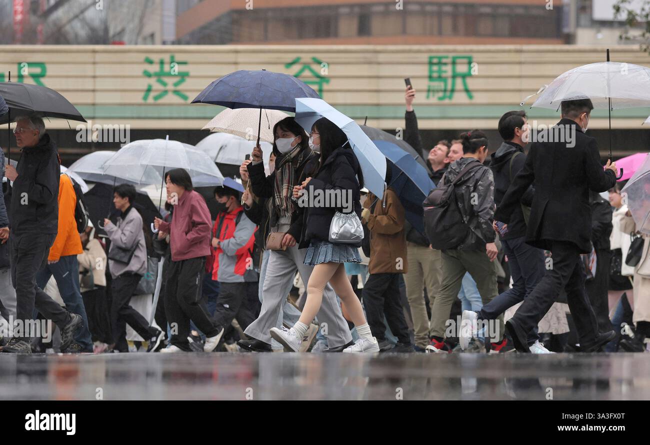 People walk with umbrella in cold rain near JR Shibuya station in ...