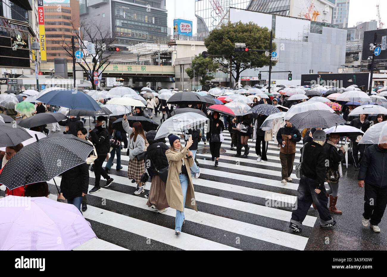 People walk with umbrella in cold rain near JR Shibuya station in ...