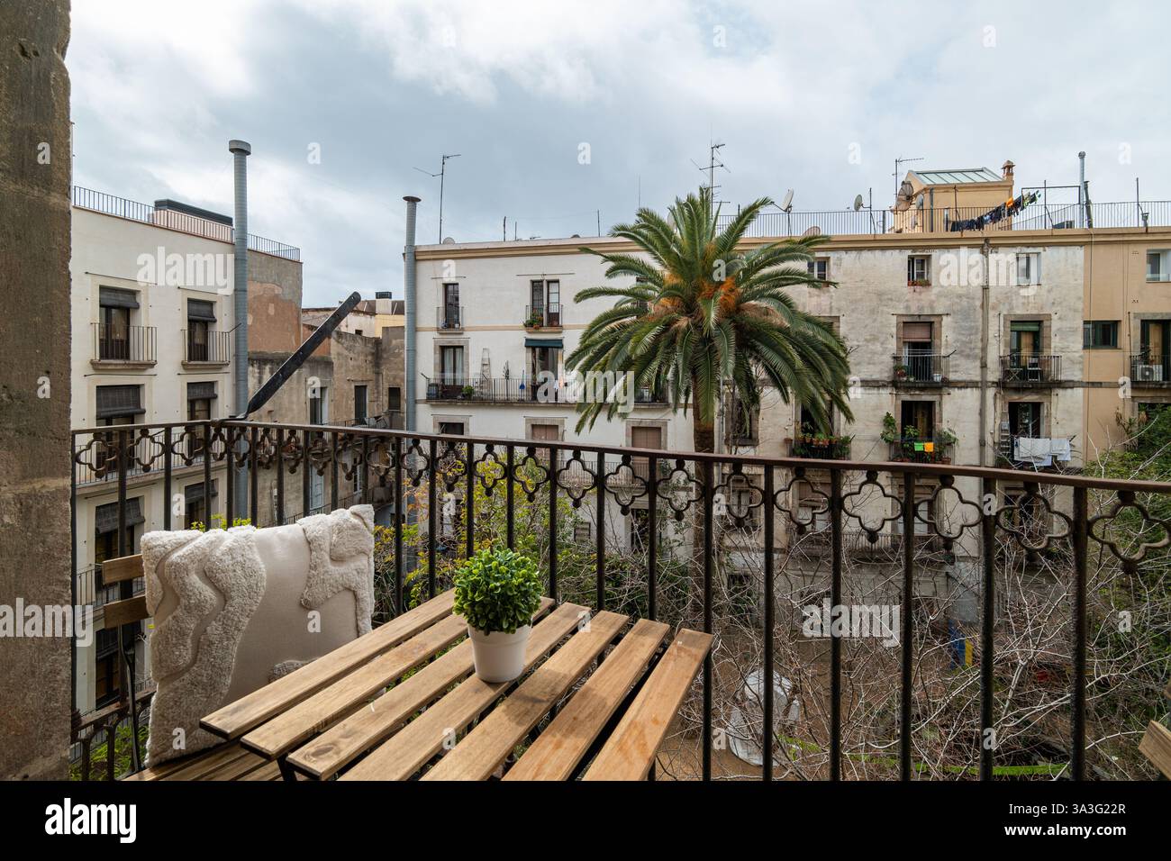Sunny balcony with green plant and wooden furniture overlooking ...