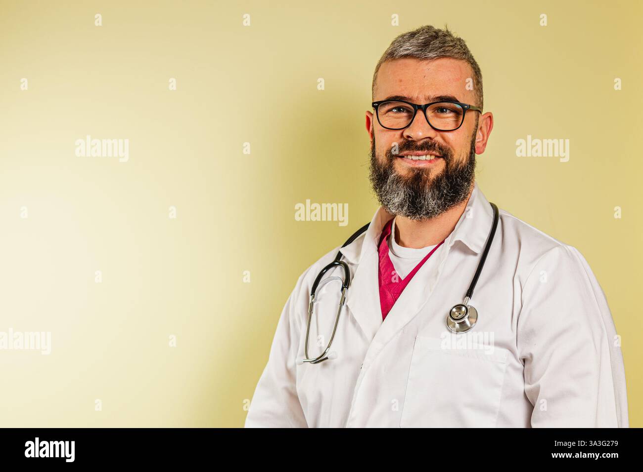 A smiling male doctor dressed in scrubs and lab coat stands confidently ...