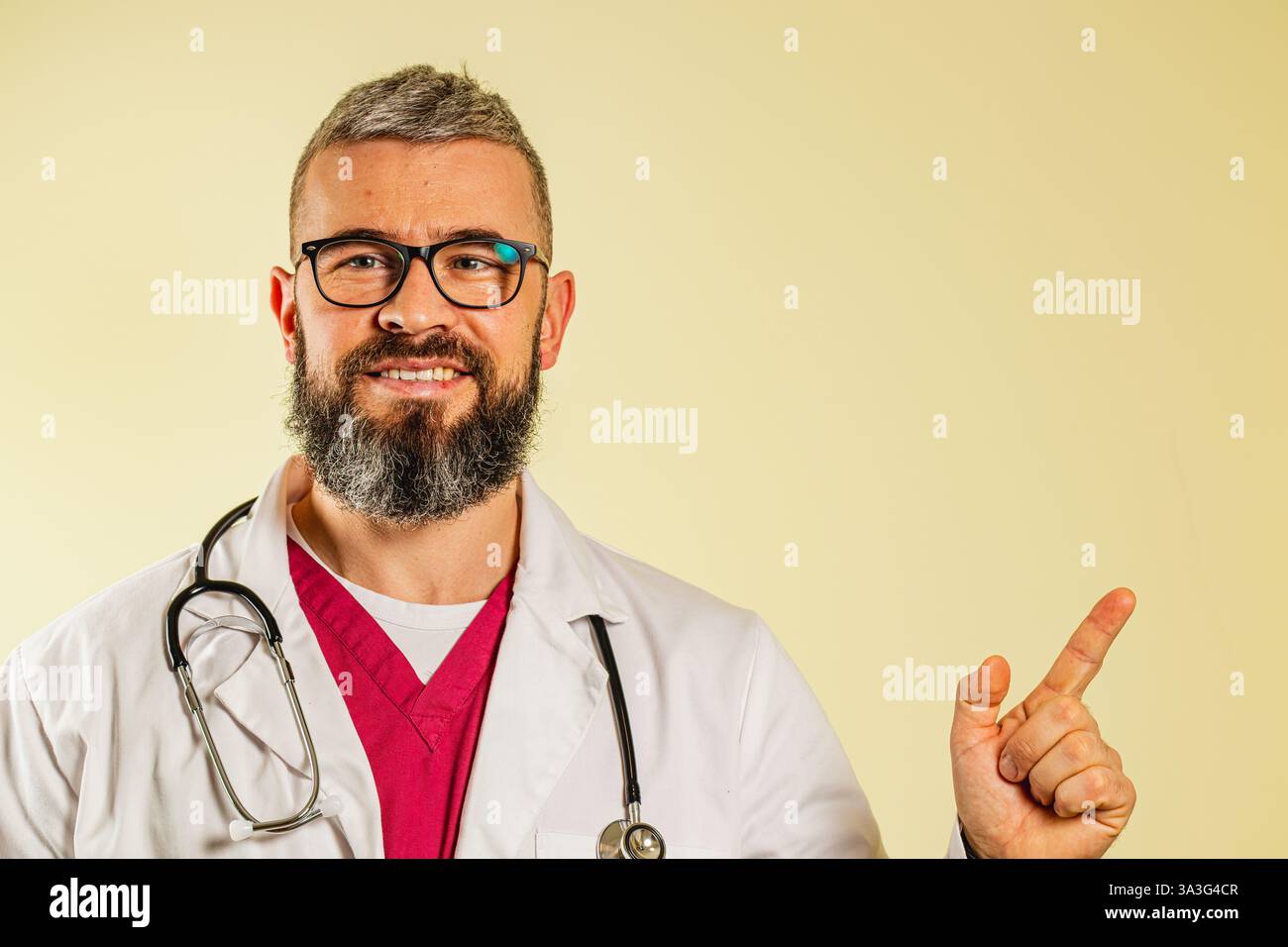 A young male cardiologist wearing scrubs and a stethoscope smiles ...