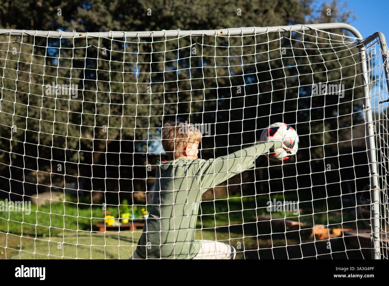 Child practicing goalkeeping, catching soccer ball in backyard Stock ...