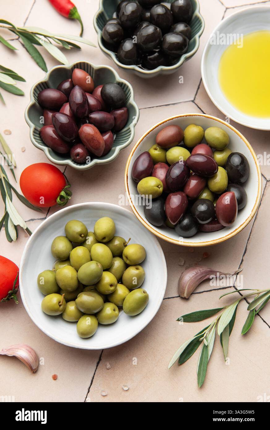 Variety of olives presented in bowls, accompanied by fresh ingredients ...