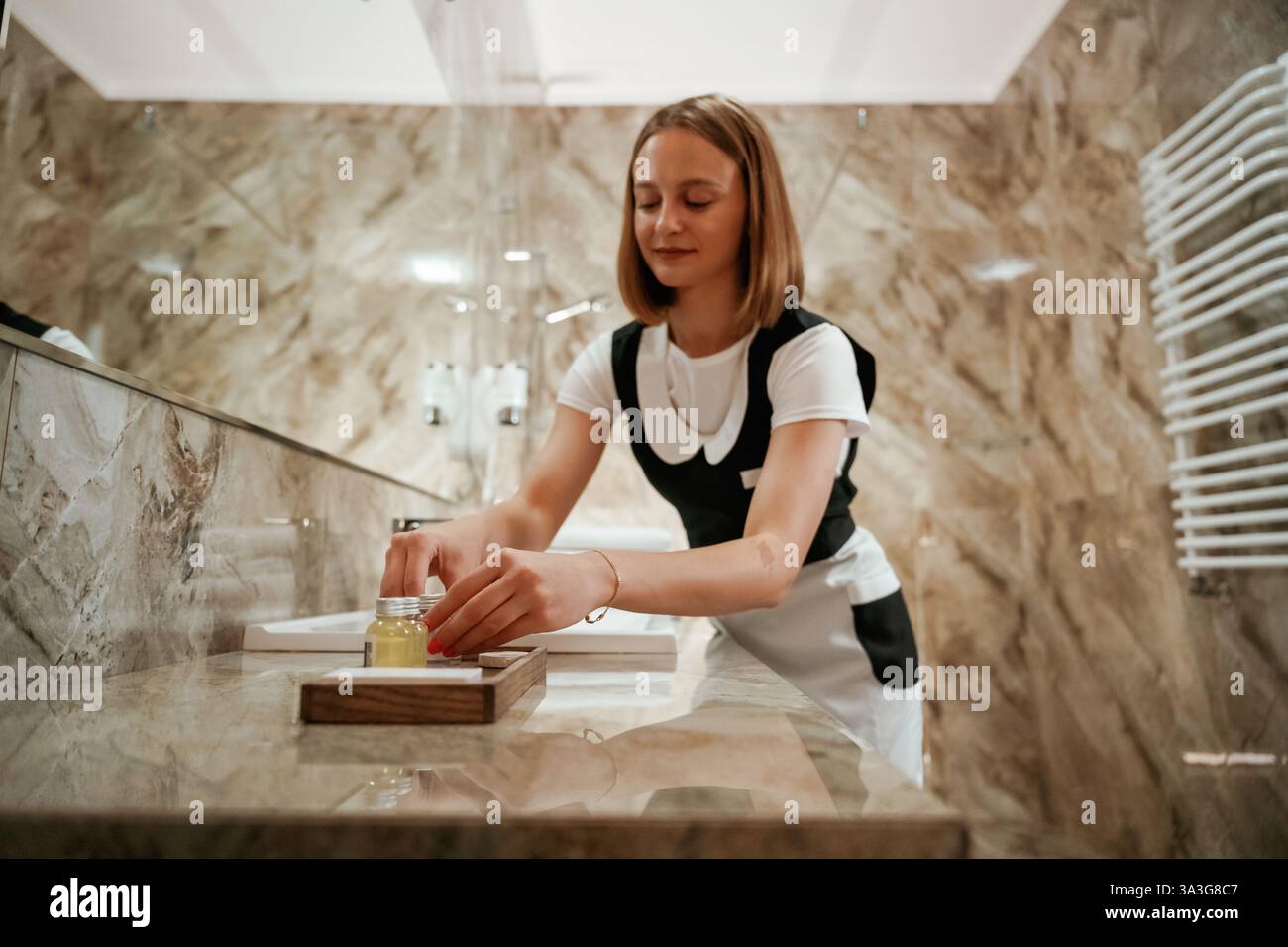 Bathroom cleaning. Young chambermaid is in hotel room Stock Photo - Alamy
