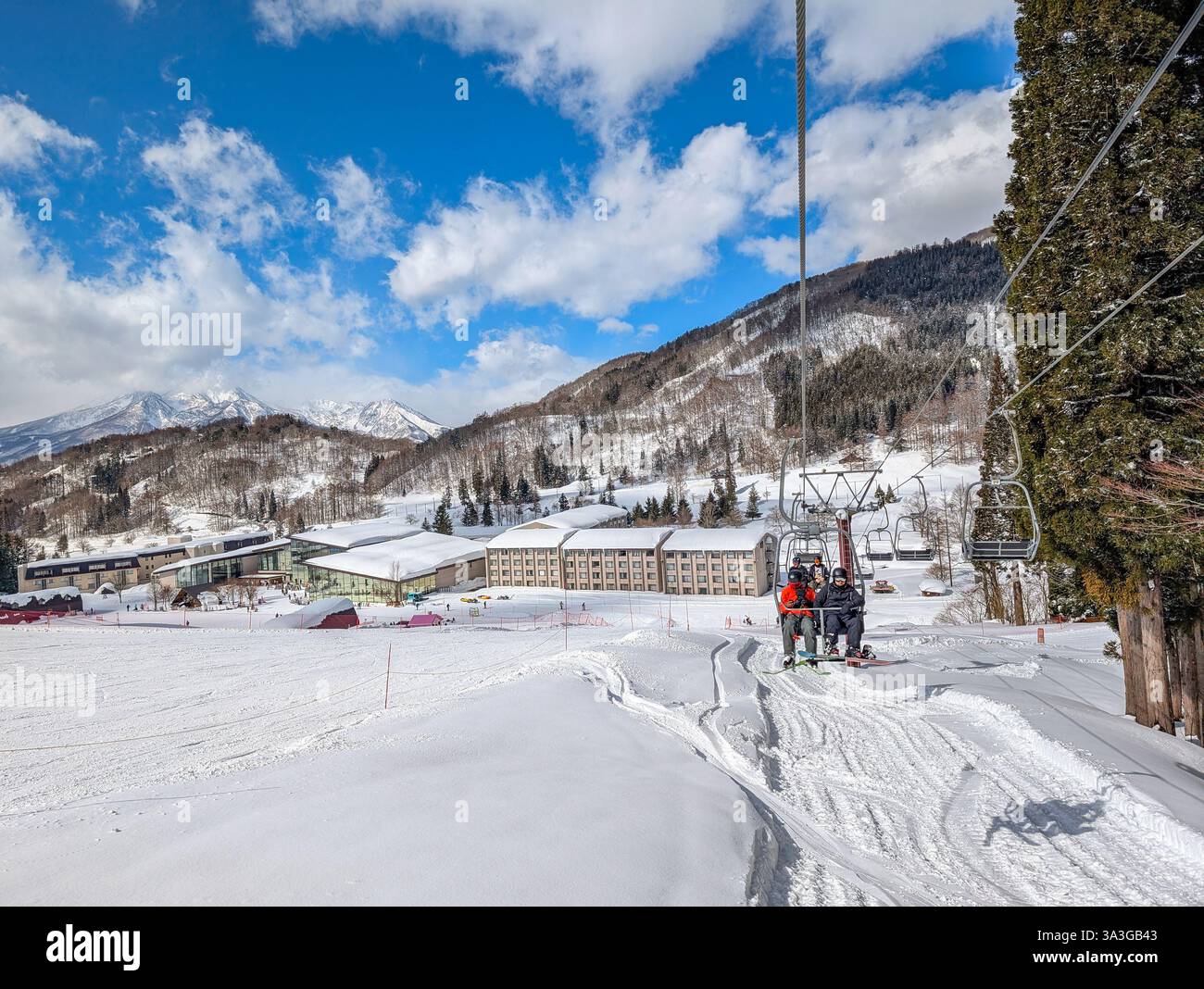 TANGRAM,JAPAN - 02 25 2025: Skiers on twin chairlift with mountain ...