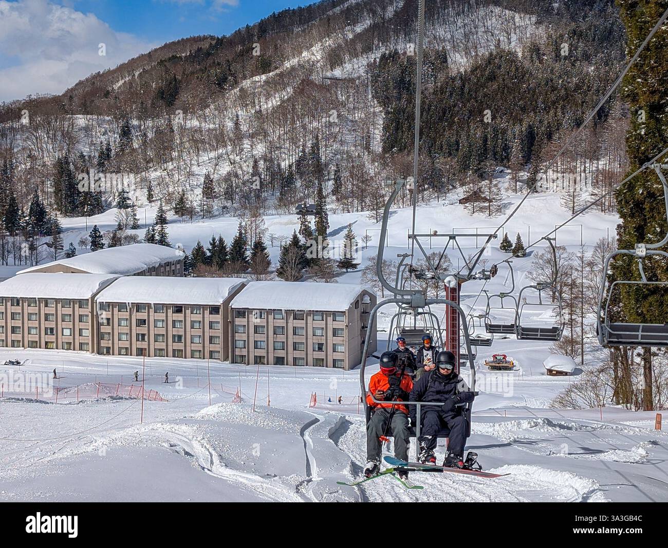 TANGRAM,JAPAN - 02 25 2025: Skiers on twin chairlift with mountain ...