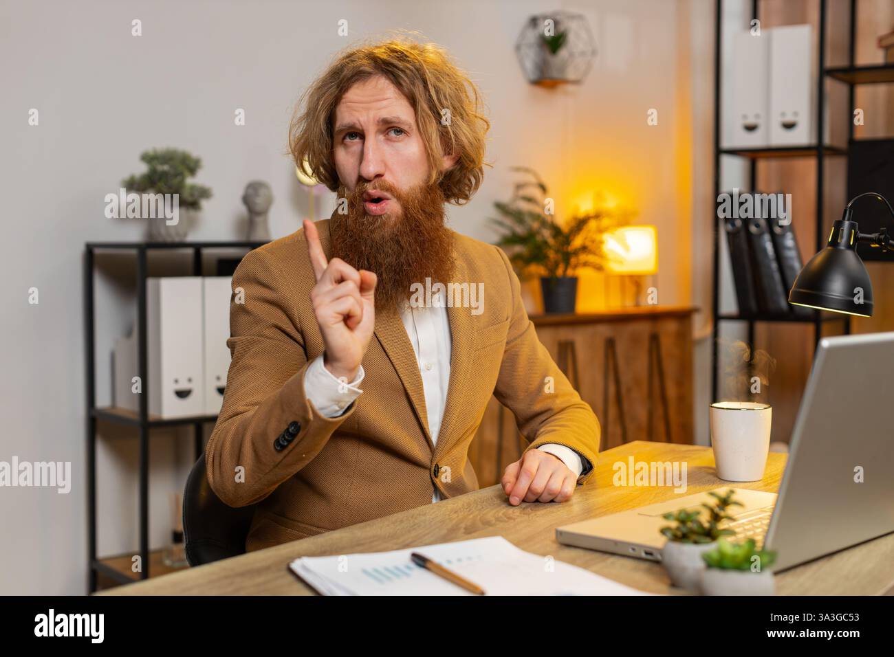 Bearded Caucasian businessman working on laptop shakes finger and ...