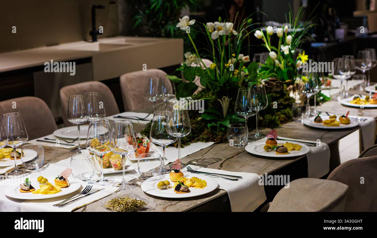 Luxurious dining table setup featuring gourmet appetizers, elegant glassware, floral centerpiece ...