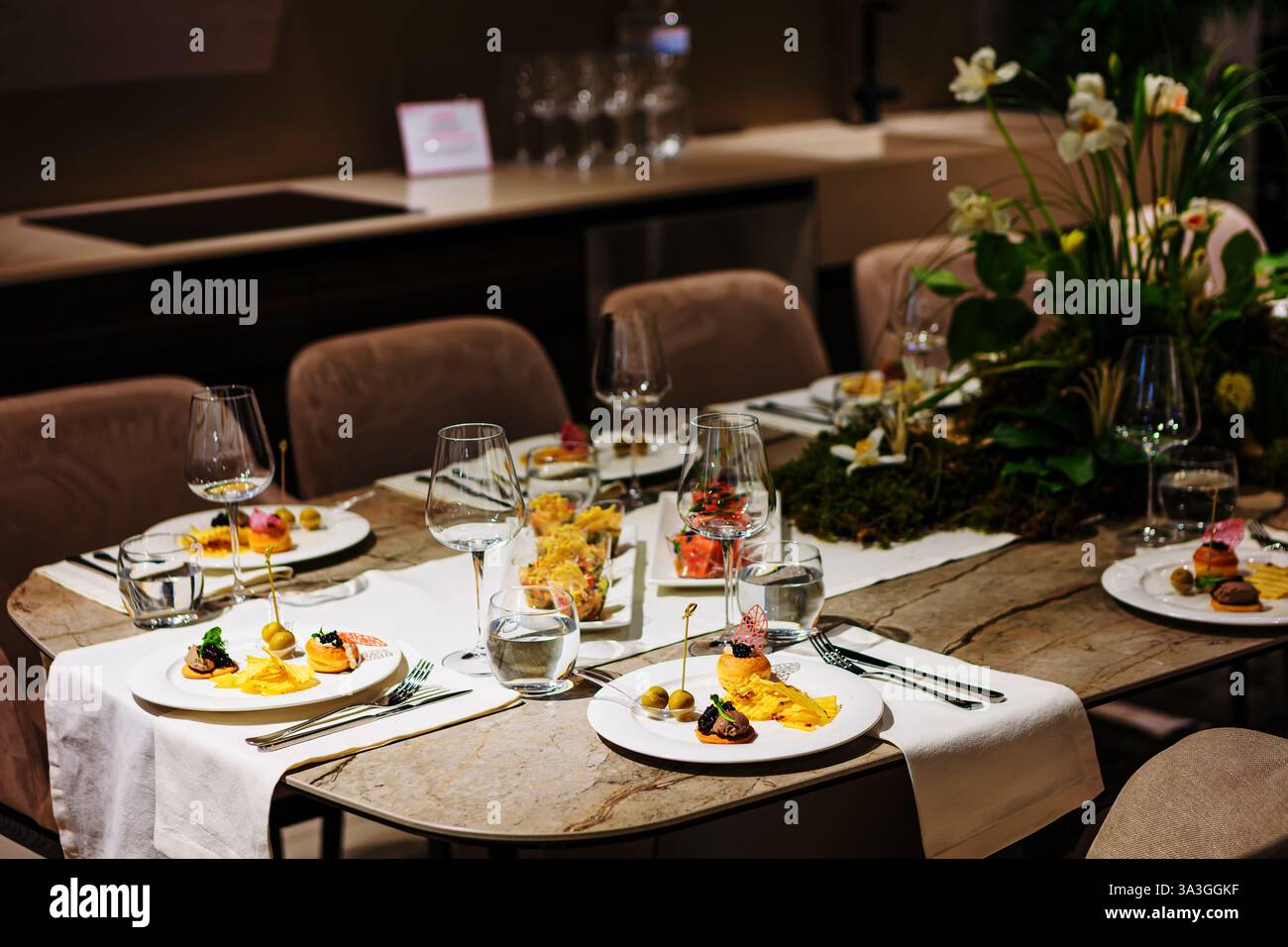 Luxurious dining table setup featuring gourmet appetizers, elegant glassware, floral centerpiece ...