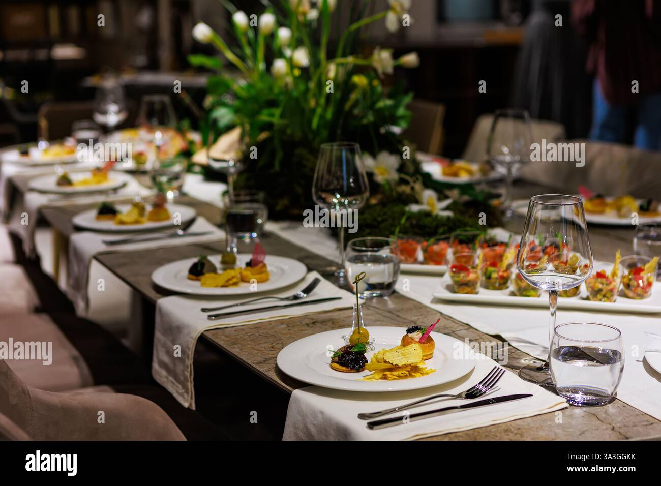 Luxurious dining table setup featuring gourmet appetizers, elegant glassware, floral centerpiece ...