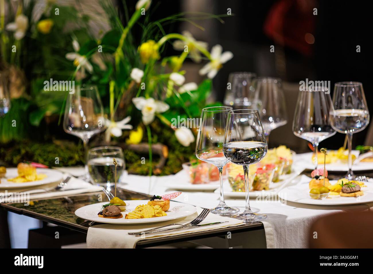 Luxurious dining table setup featuring gourmet appetizers, elegant glassware, floral centerpiece ...