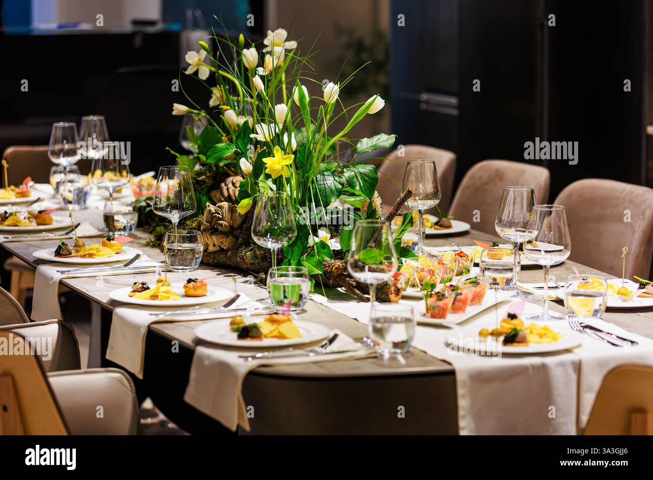 Elegant floral centerpiece with white tulips and lush greenery on a luxurious dining table Stock ...
