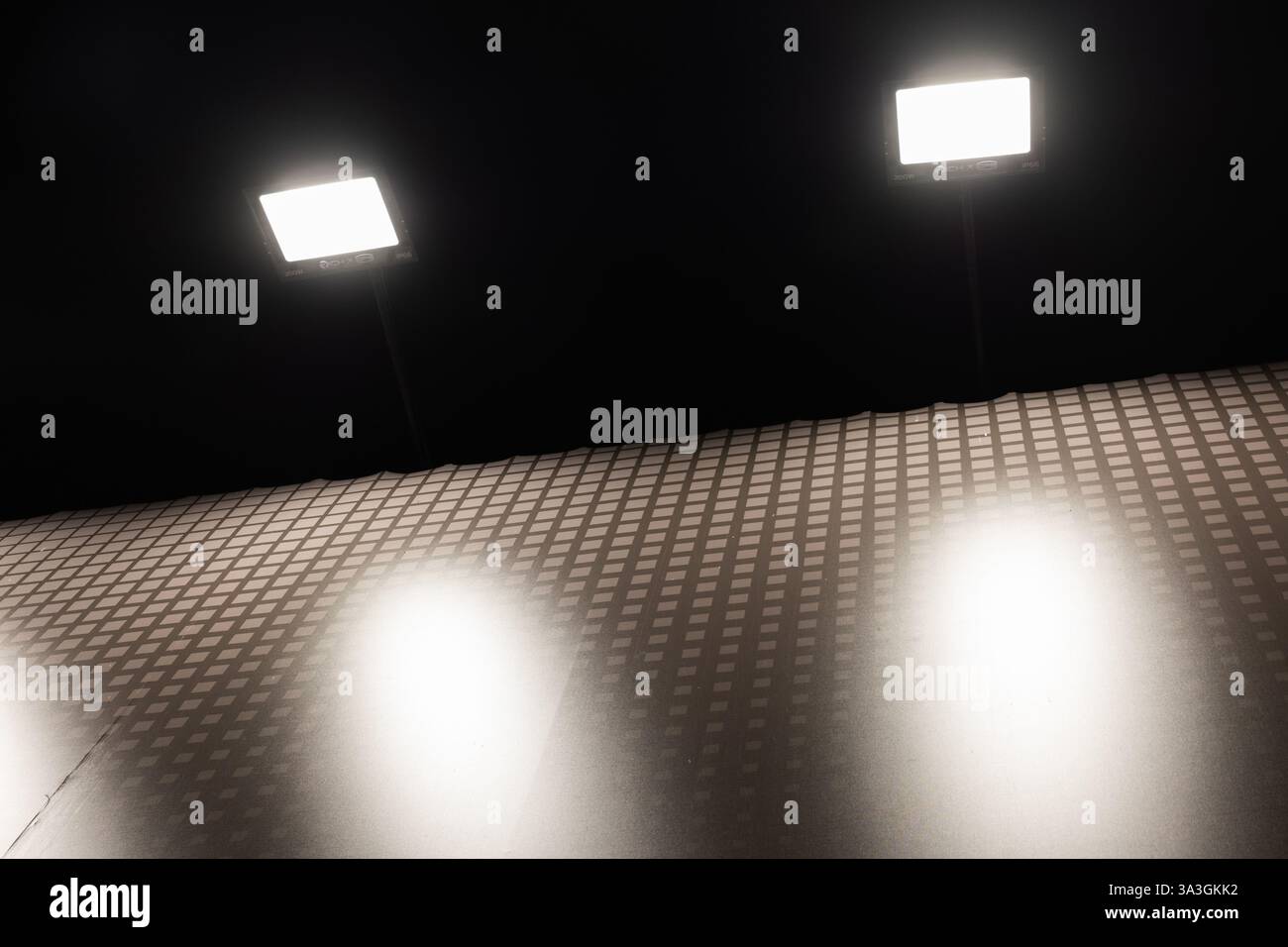 A textured wall illuminated by modern square lights at night, casting ...