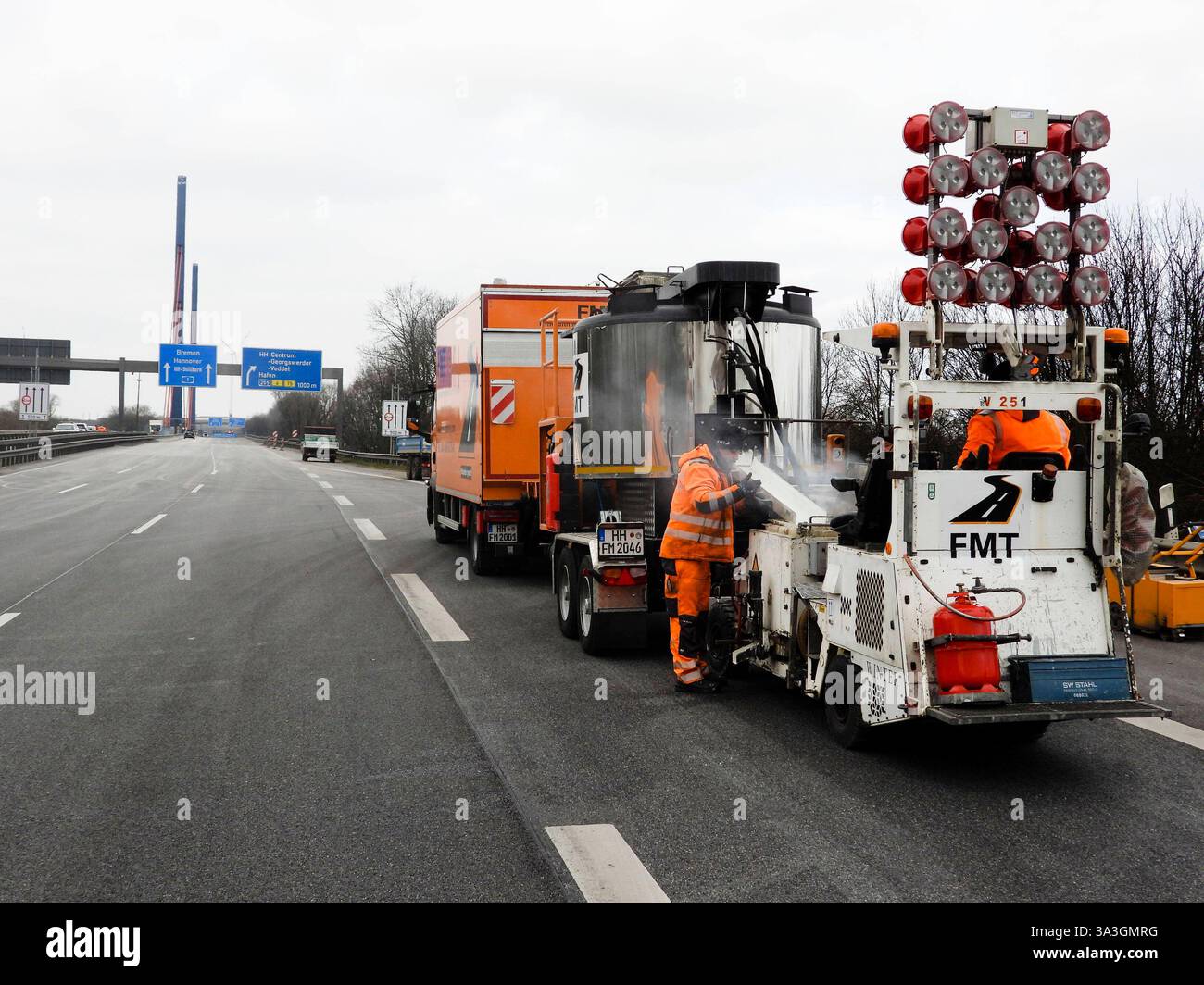 Strassenbauatbeiter der Firma FTM in Orangener Schutzkleidung bringen ...