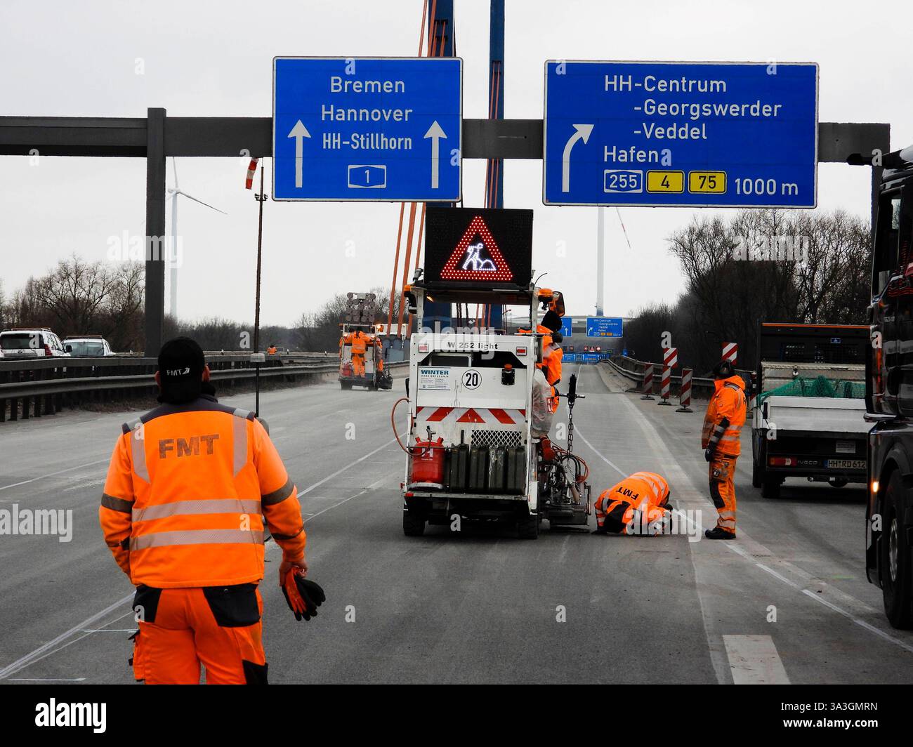 Strassenbauatbeiter der Firma FTM in Orangener Schutzkleidung bringen ...