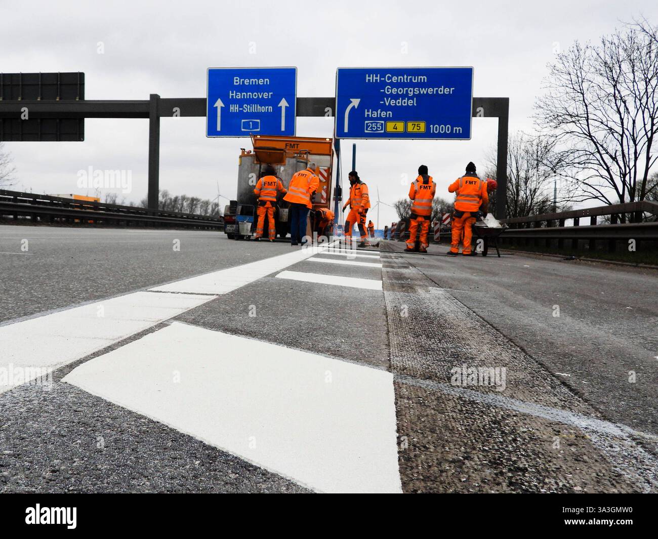 Strassenbauatbeiter der Firma FTM in Orangener Schutzkleidung bringen ...
