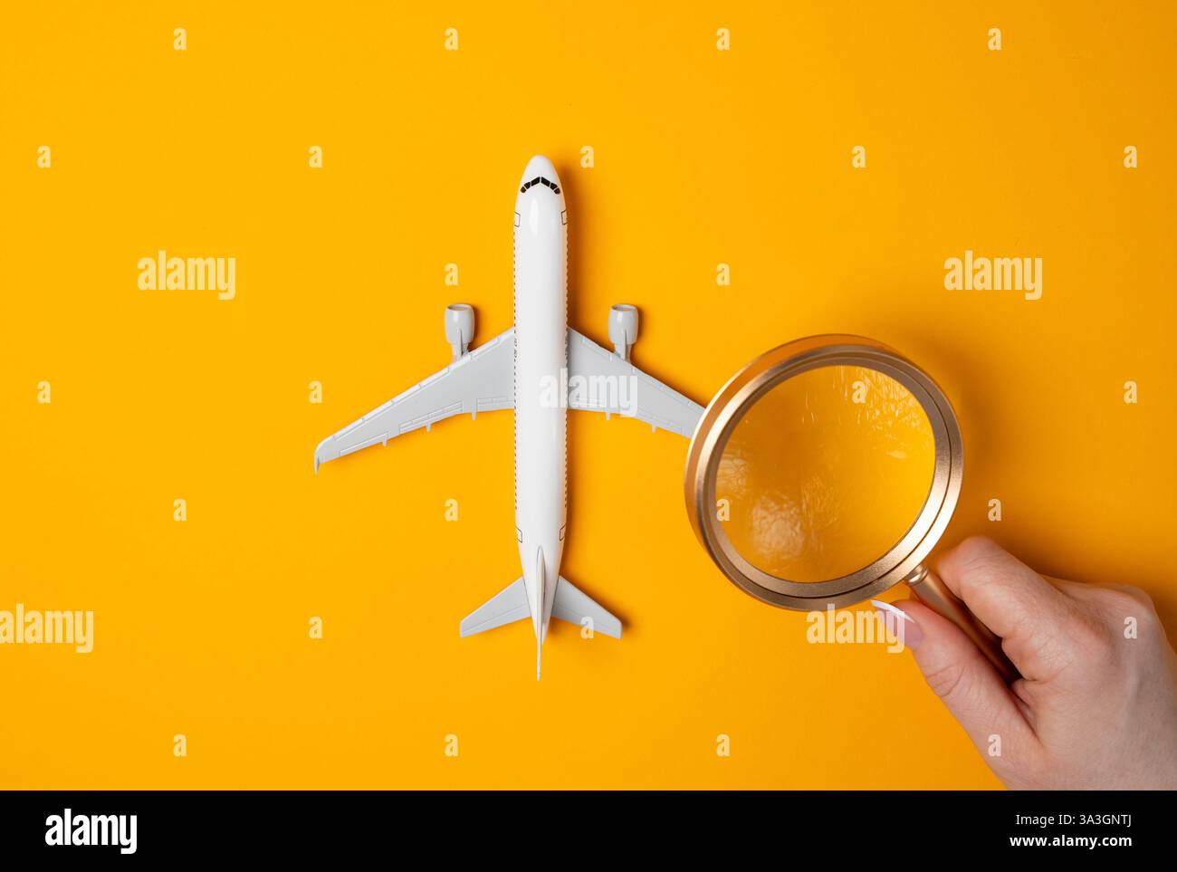 A woman examines a passenger plane under a magnifying glass. Airline ...