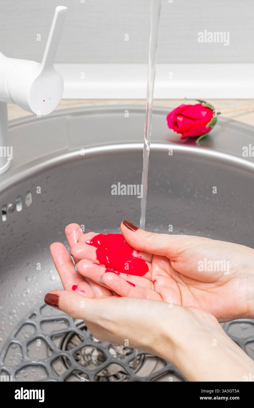 woman washes her hands with red soap. soap flower near the sink. woman ...