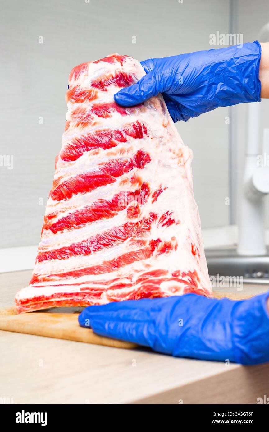 housewife cooking pork ribs in home kitchen. hand holding pork rib ...