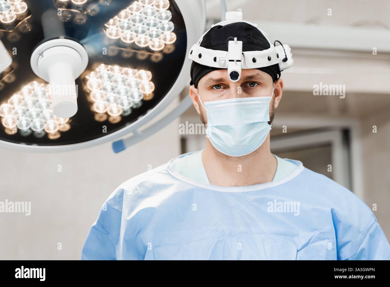 Portrait of male surgeon with headlight in the operating room before ...