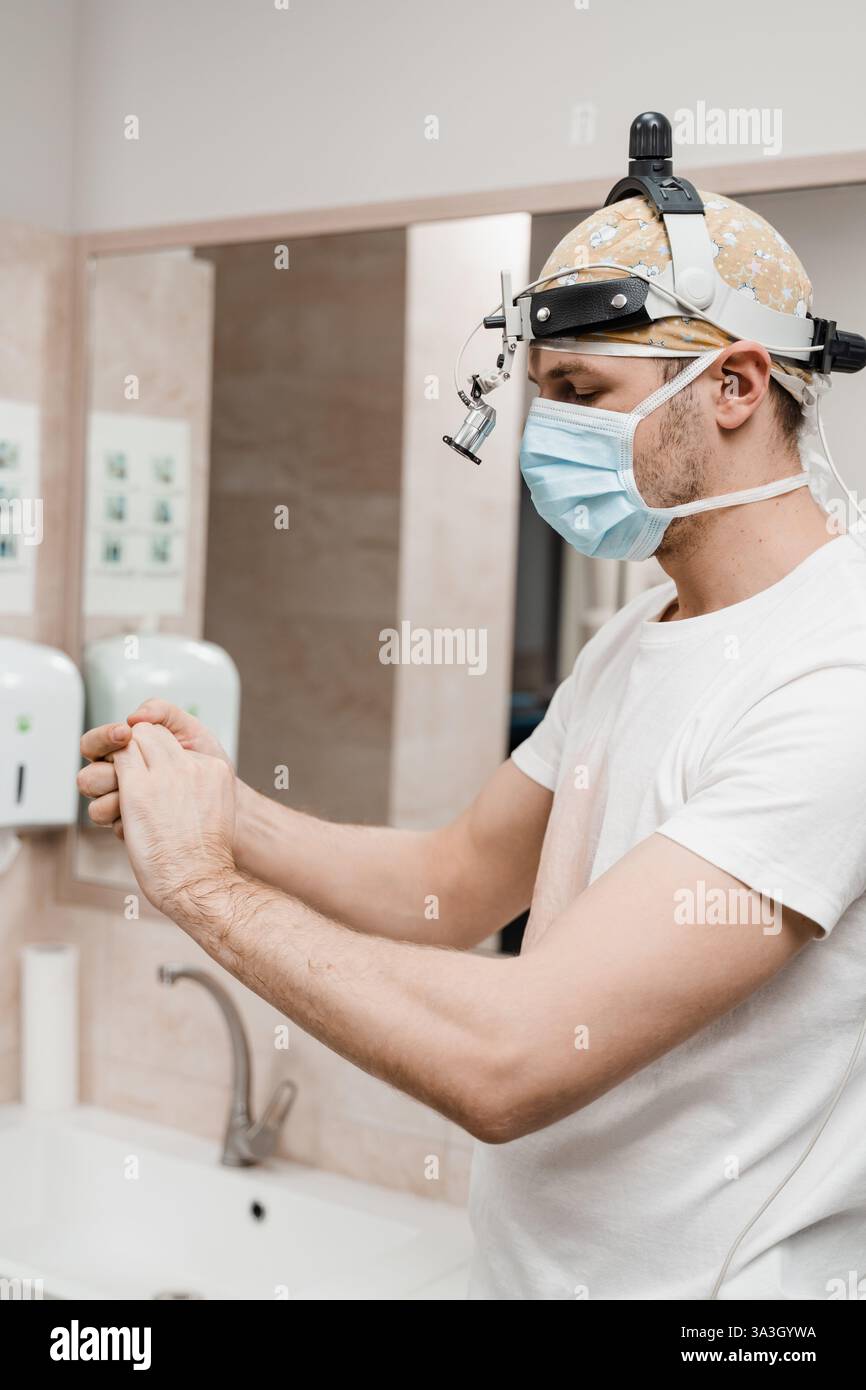 Surgeon with headlight is washing hands before surgery in medical ...