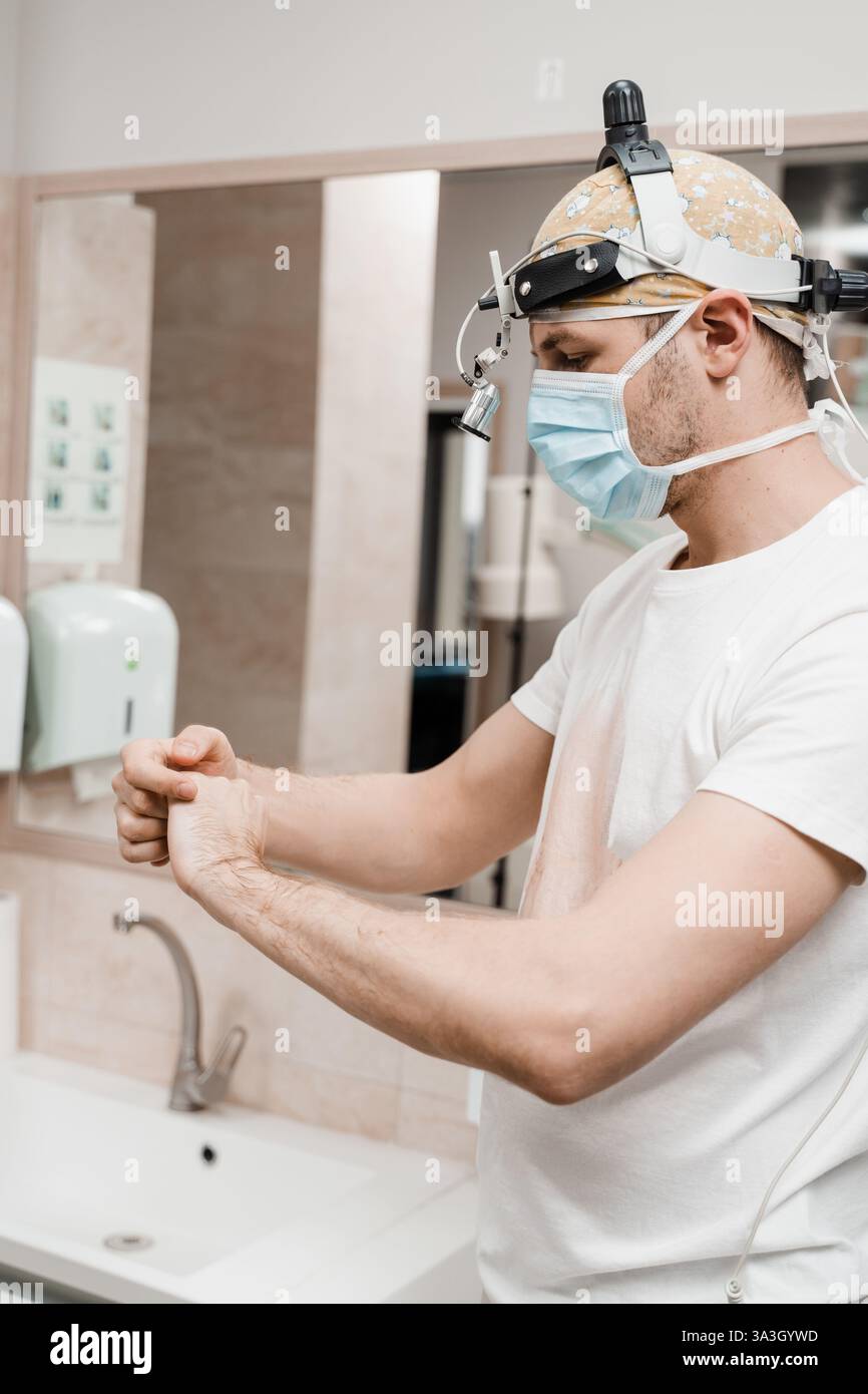 Surgeon with headlight is washing hands before surgery in medical ...