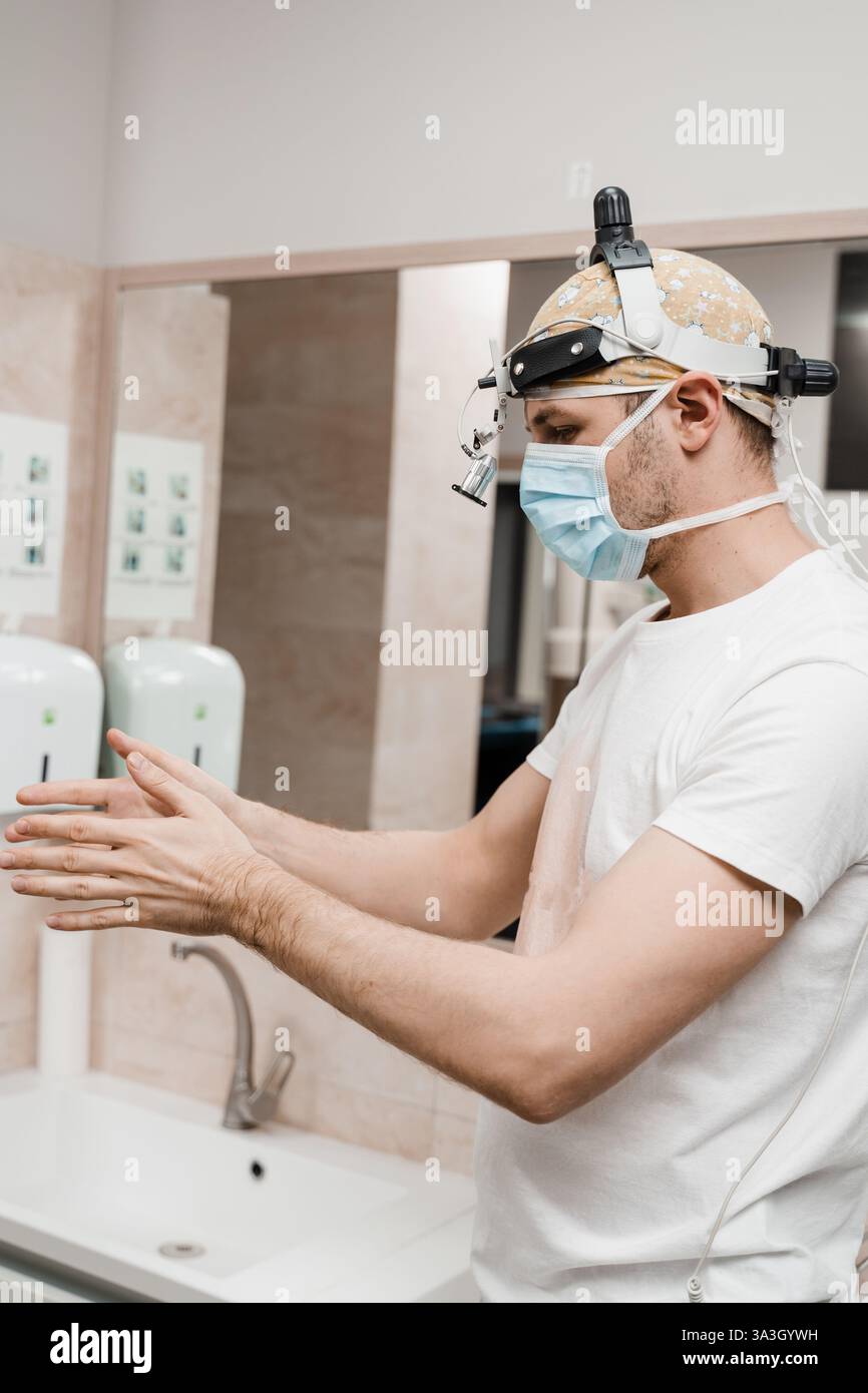 Surgeon with headlight is washing hands before surgery in medical ...