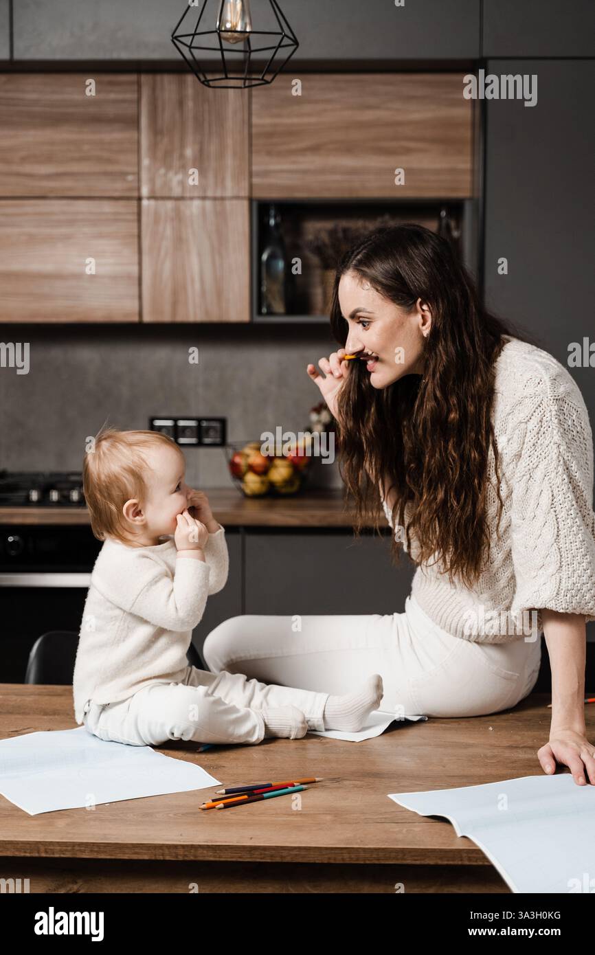 Mom and daughter toddler fool around and play together in the kitchen ...