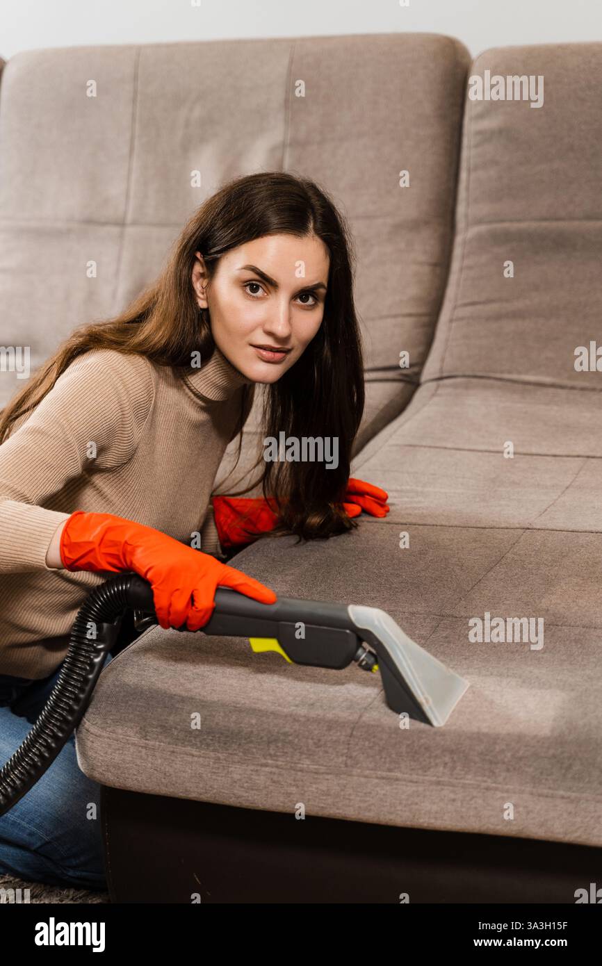 Cleaner girl is cleaning couch with extractor machine for dry clean ...