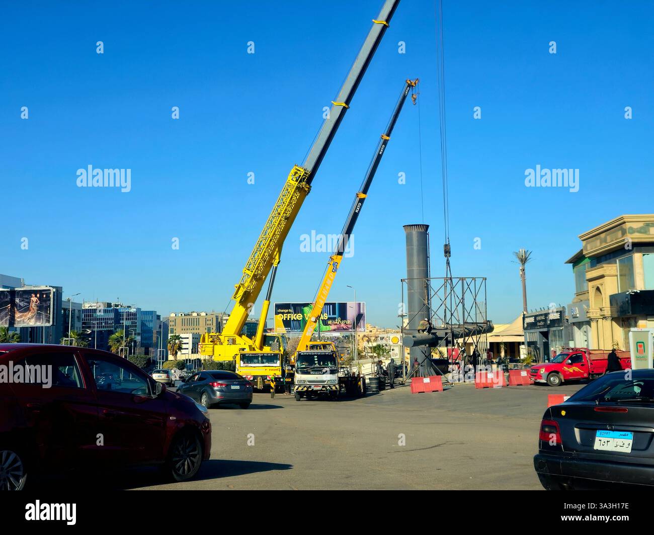 Cairo, Egypt, February 27 2025: mobile cranes fitting a steel structure advertising board in ...