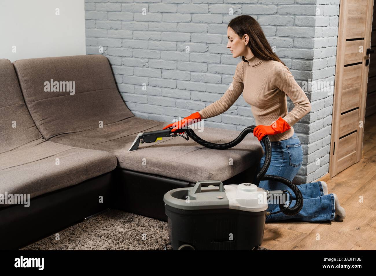 Cleaner girl is cleaning couch with extractor machine for dry clean ...