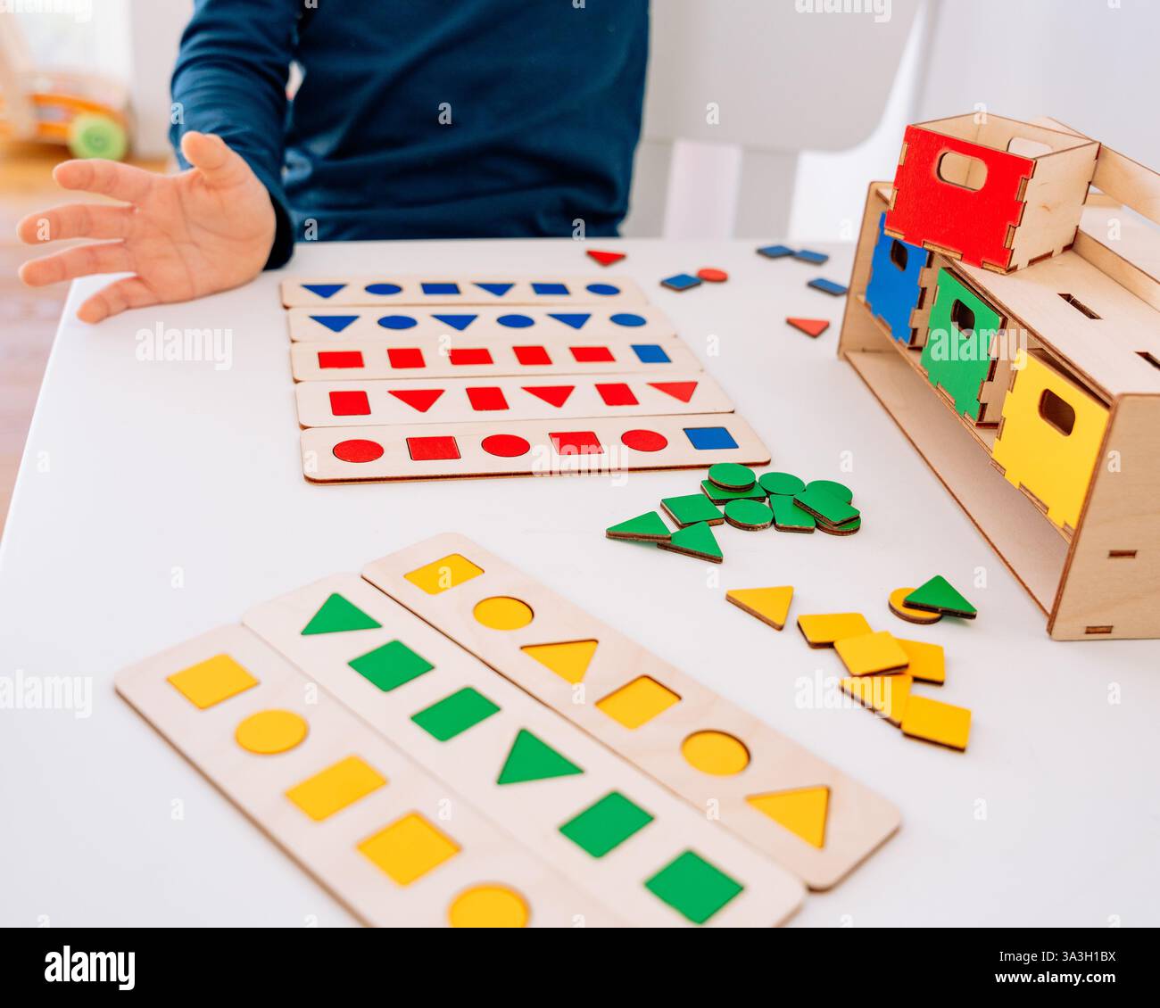 A child carefully places colorful wooden geometric figures circle ...