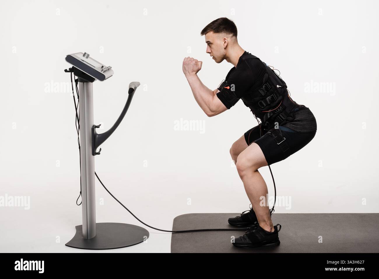 Muscular male athlete does squats physical exercises in EMS suit that ...