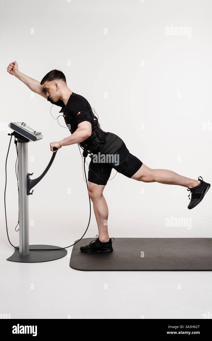 Male athlete with muscular build does workout using EMS suit, which ...