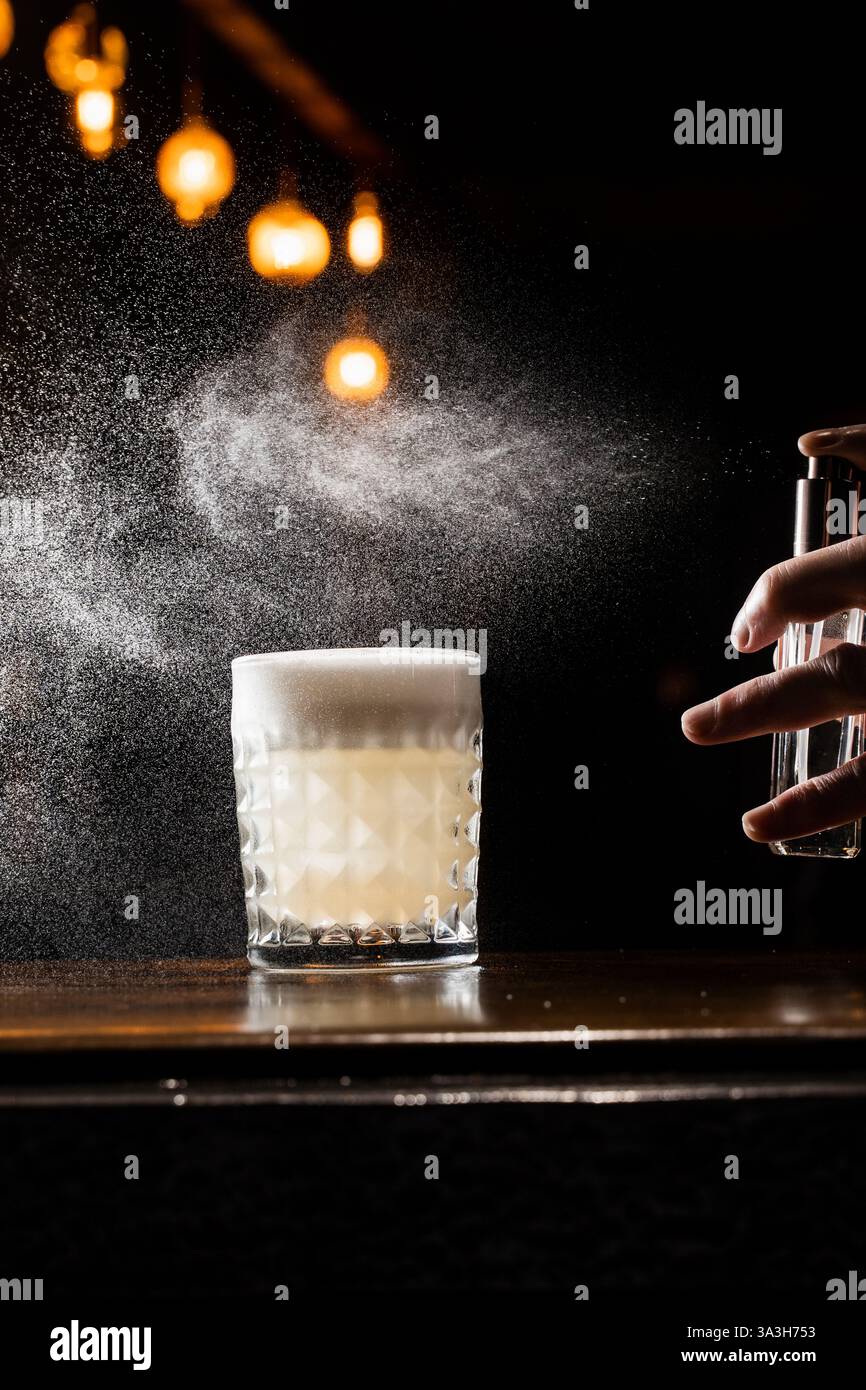 Bartender is spraying whiskey over Penicillin coctail. Alcohol cocktail ...