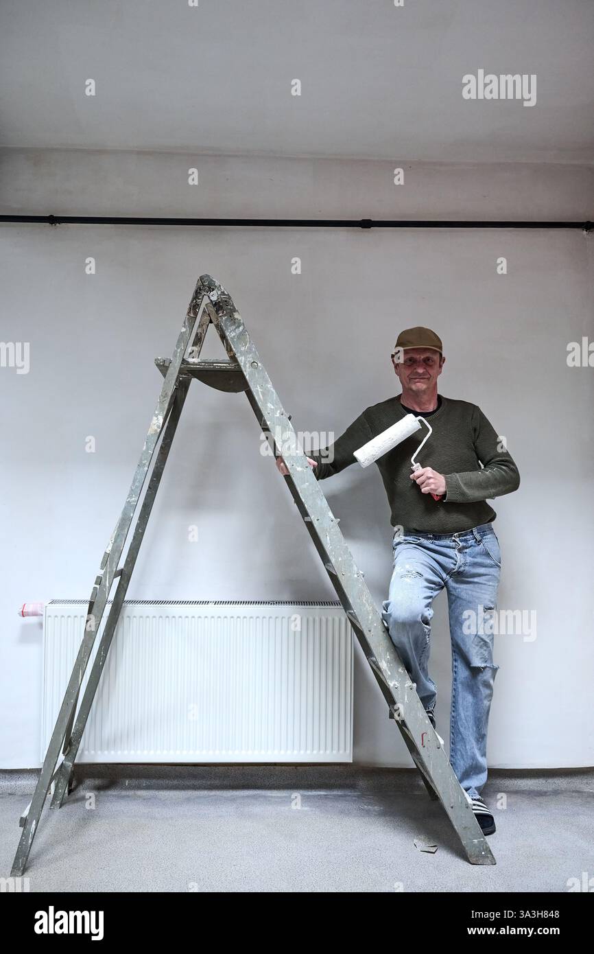 Painter in dirty clothes posing against ladder in loft Stock Photo - Alamy