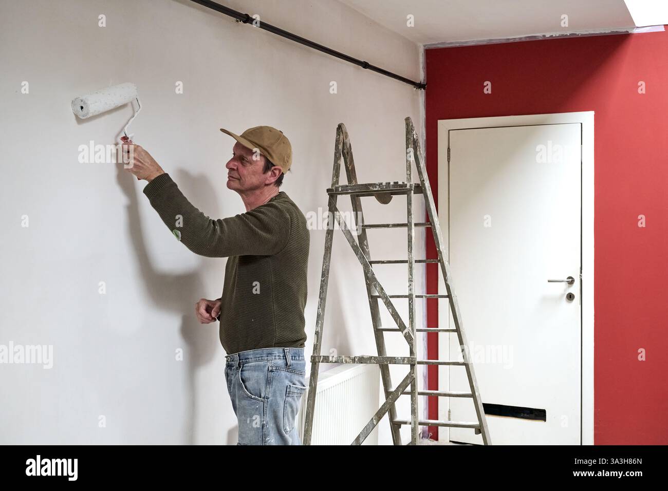 Painter in dirty clothes renovate a wall in a loft Stock Photo - Alamy