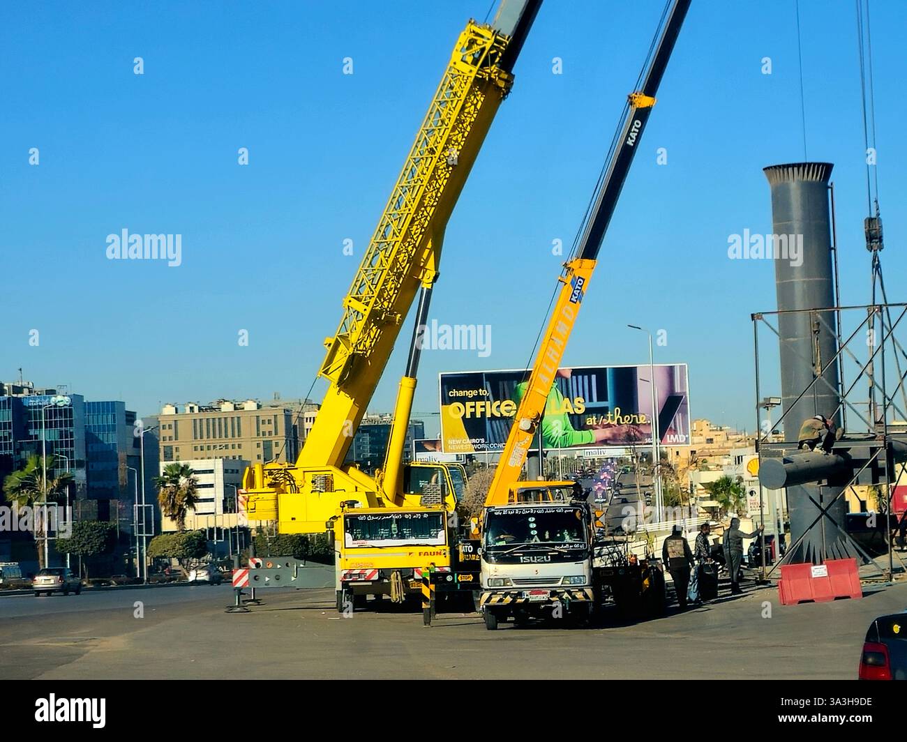 Cairo, Egypt, February 27 2025: mobile cranes fitting a steel structure advertising board in ...