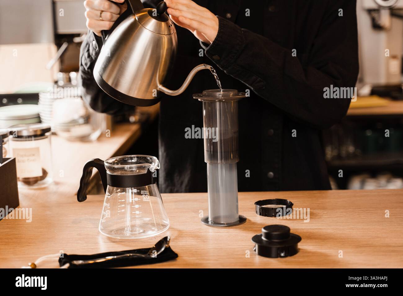 Pouring hot water over roasted and ground coffee beans in aeropress ...
