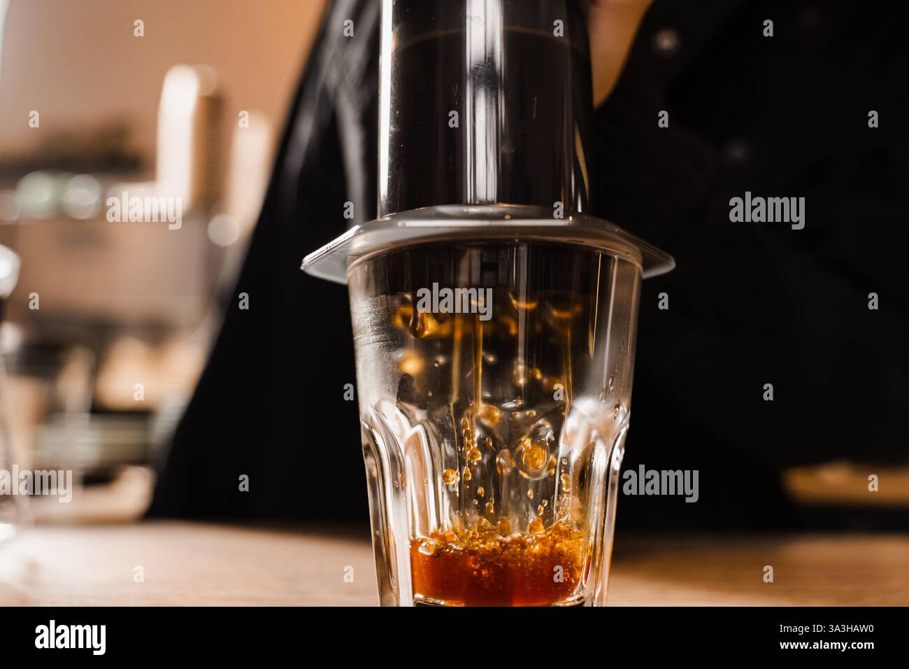 Aeropress coffee. Process of pouring coffee in cup. Barista is pushing ...