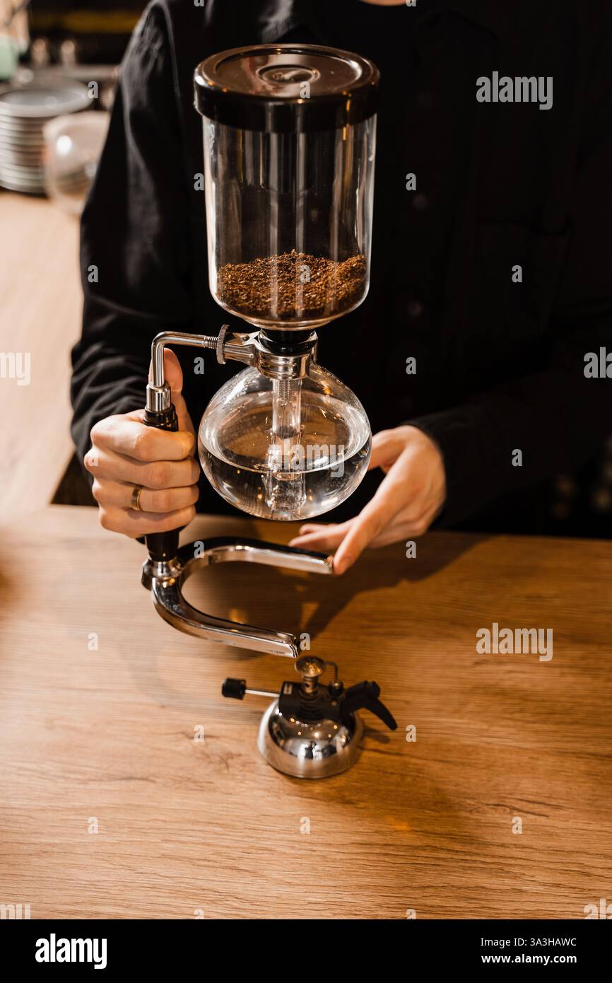 Process of brewing siphon coffee in cafe. Barista is holding siphon ...