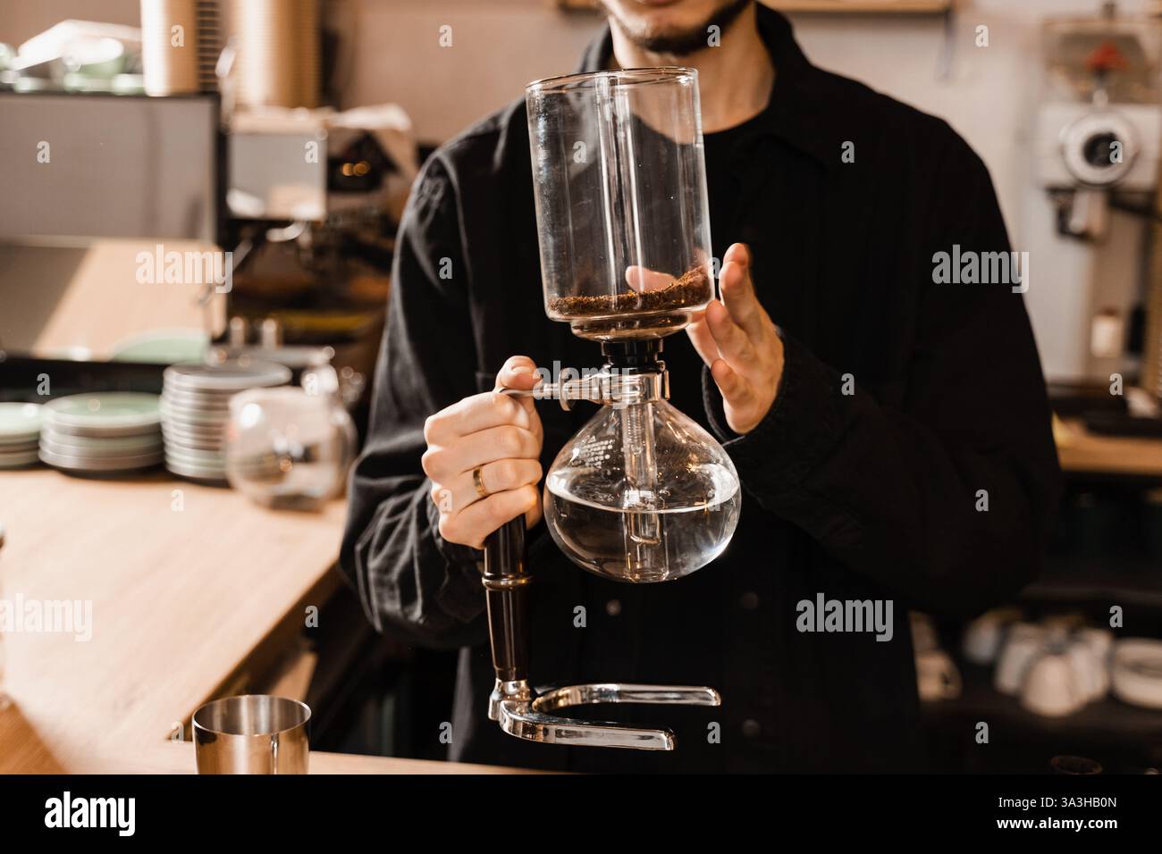 Barista is holding siphon before starting boiling water inside syphon ...