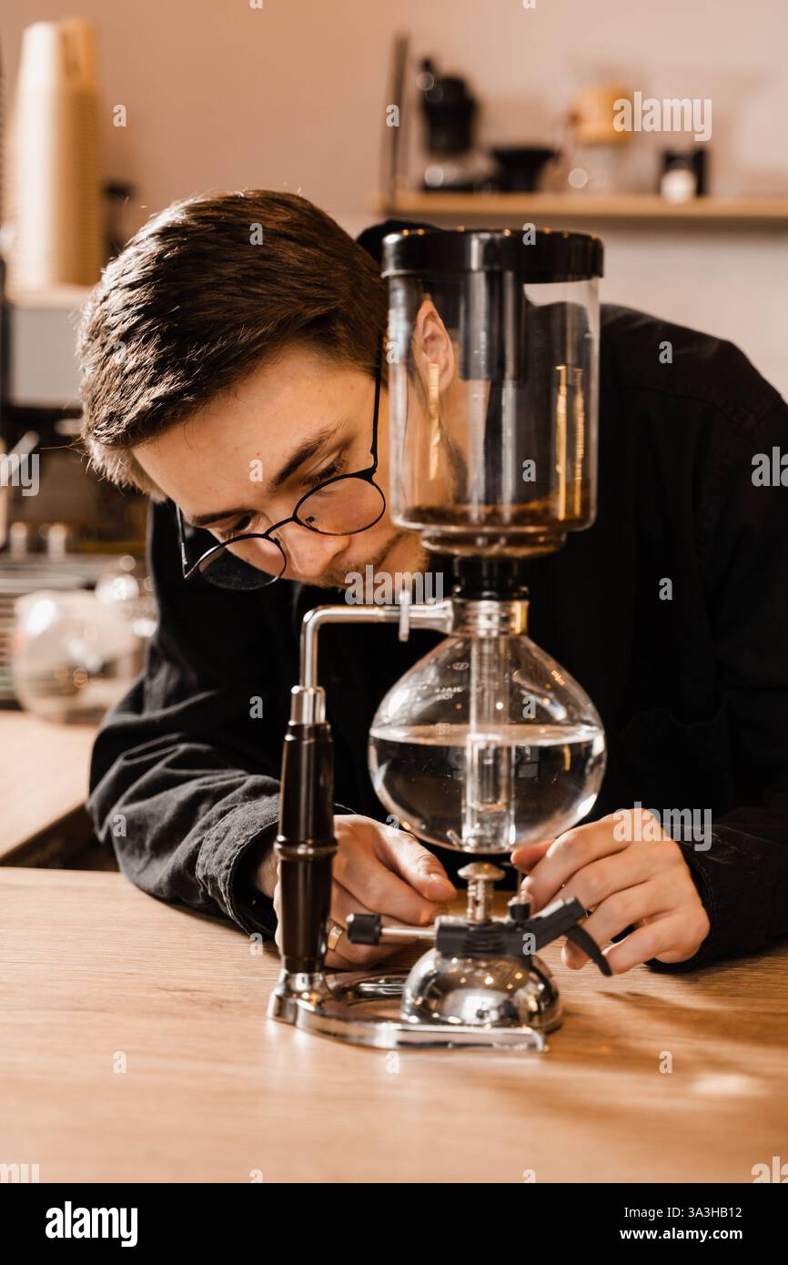 Barista is boil water in syphon device for alternative brewing coffee ...