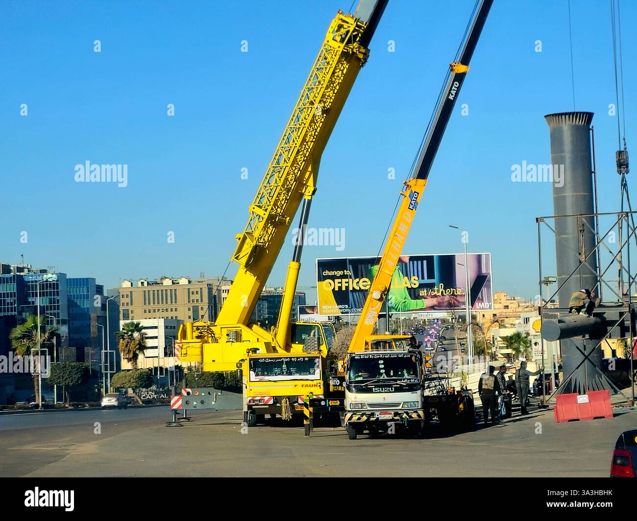 Cairo, Egypt, February 27 2025: mobile cranes fitting a steel structure advertising board in ...
